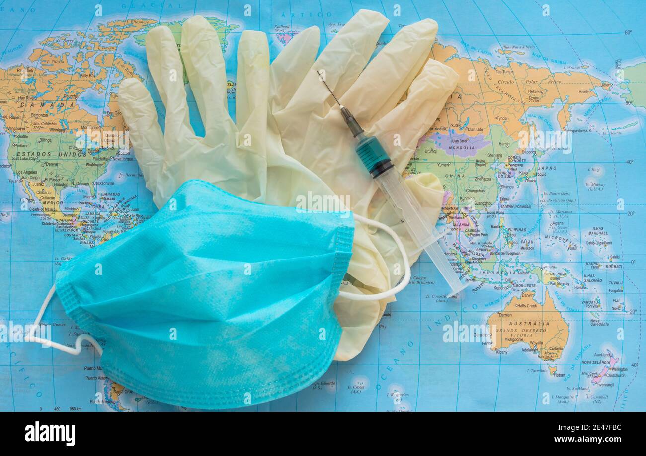 Gloves, a syringe and a face mask on a world map - global pandemic ...