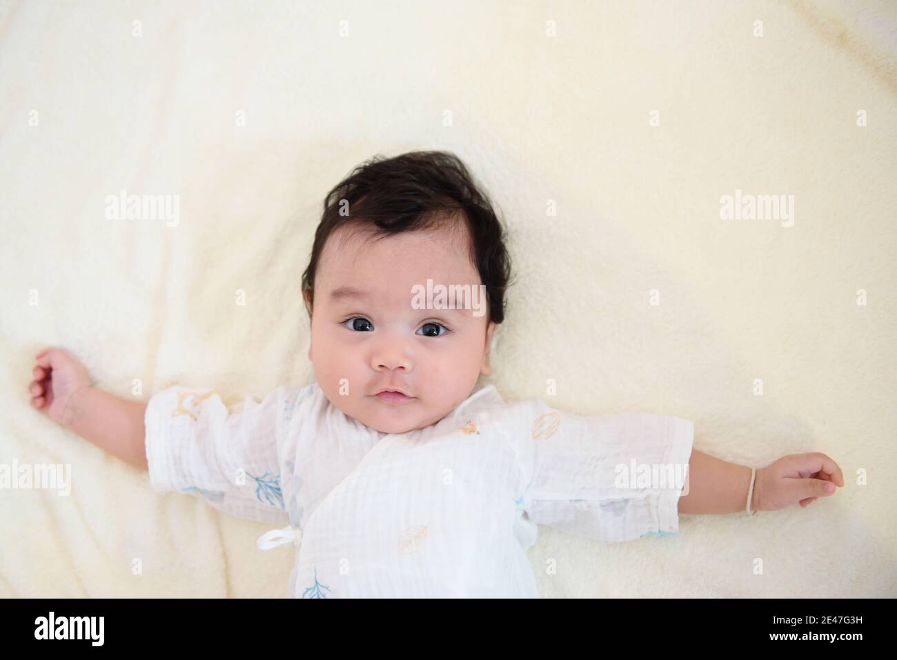 Top view of cute little Asian baby cheerful and looking at the camera ...