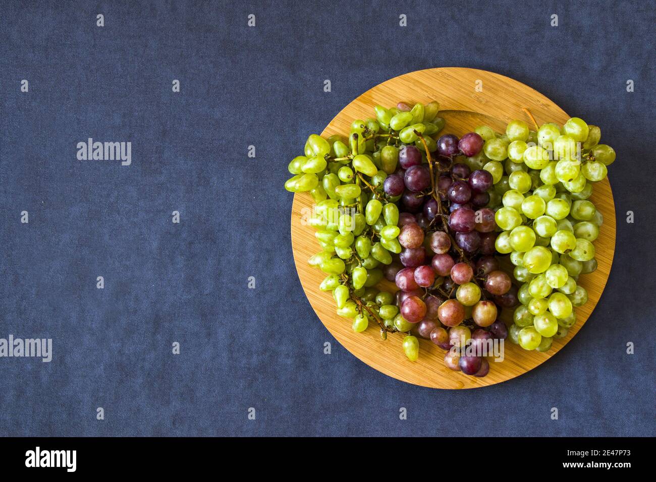 Overhead shot of different kinds of grapes in a plate on a blue ...