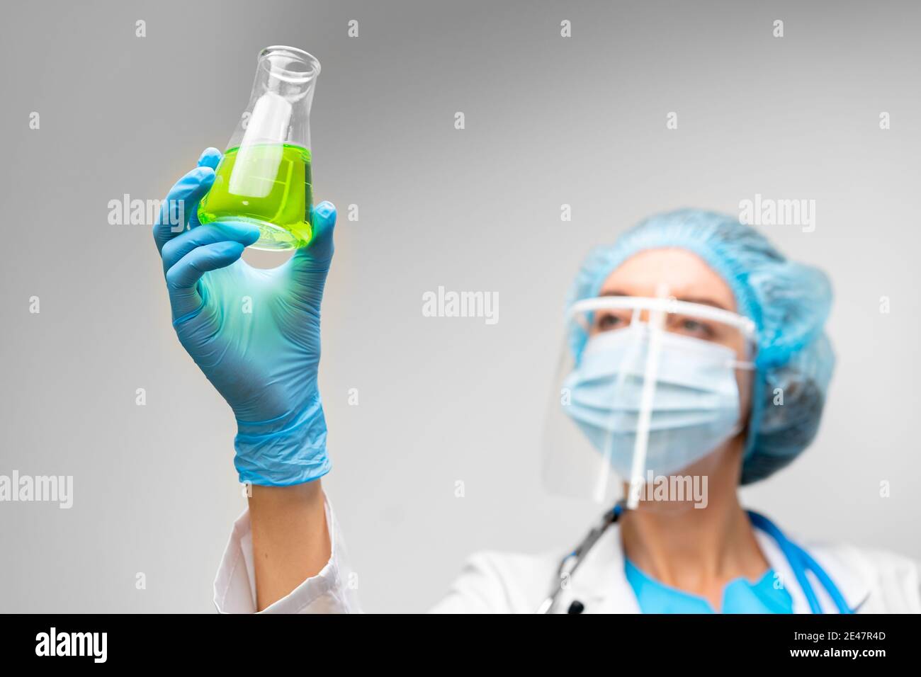 Woman scientist holding laboratory flask with chemical liquid, gray ...