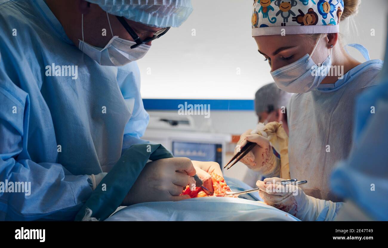 Plastic surgeon and assistant wearing medical face masks and sterile ...