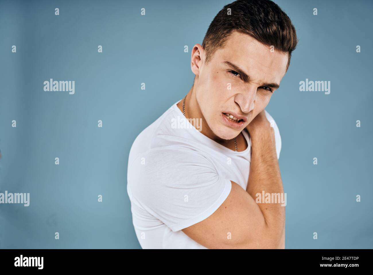 emotional displeased man cropped view white t-shirt blue background ...