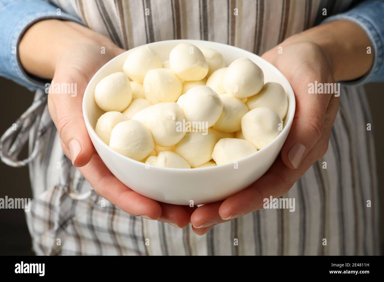Woman in apron hold bowl with mozzarella cheese, front view Stock Photo ...