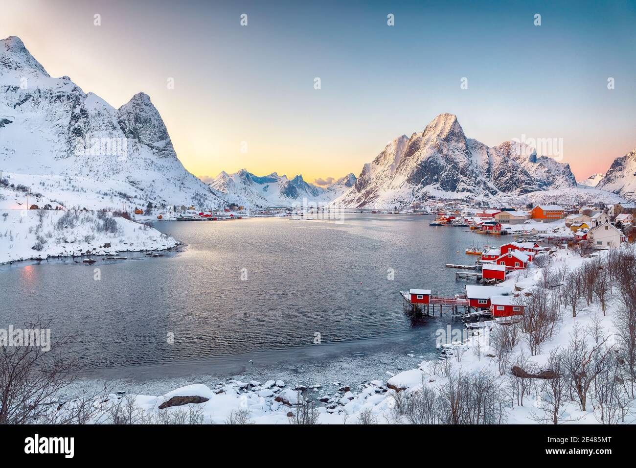 Dramatic evening cityscape of Reine town. Red rorbuers on the shore of ...