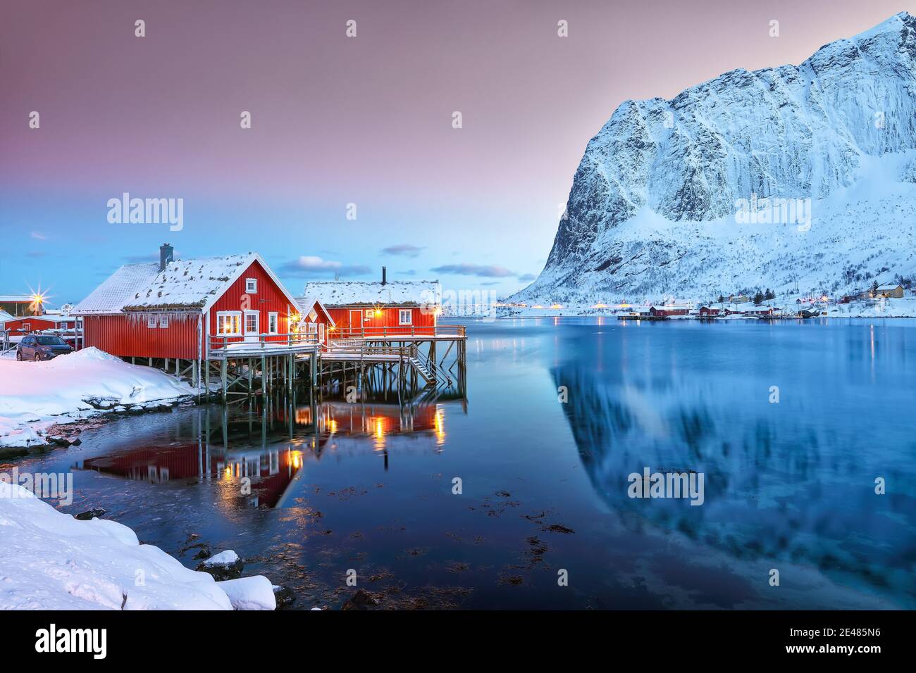 Dramatic evening cityscape of Reine town. Red rorbuers on the shoore of ...