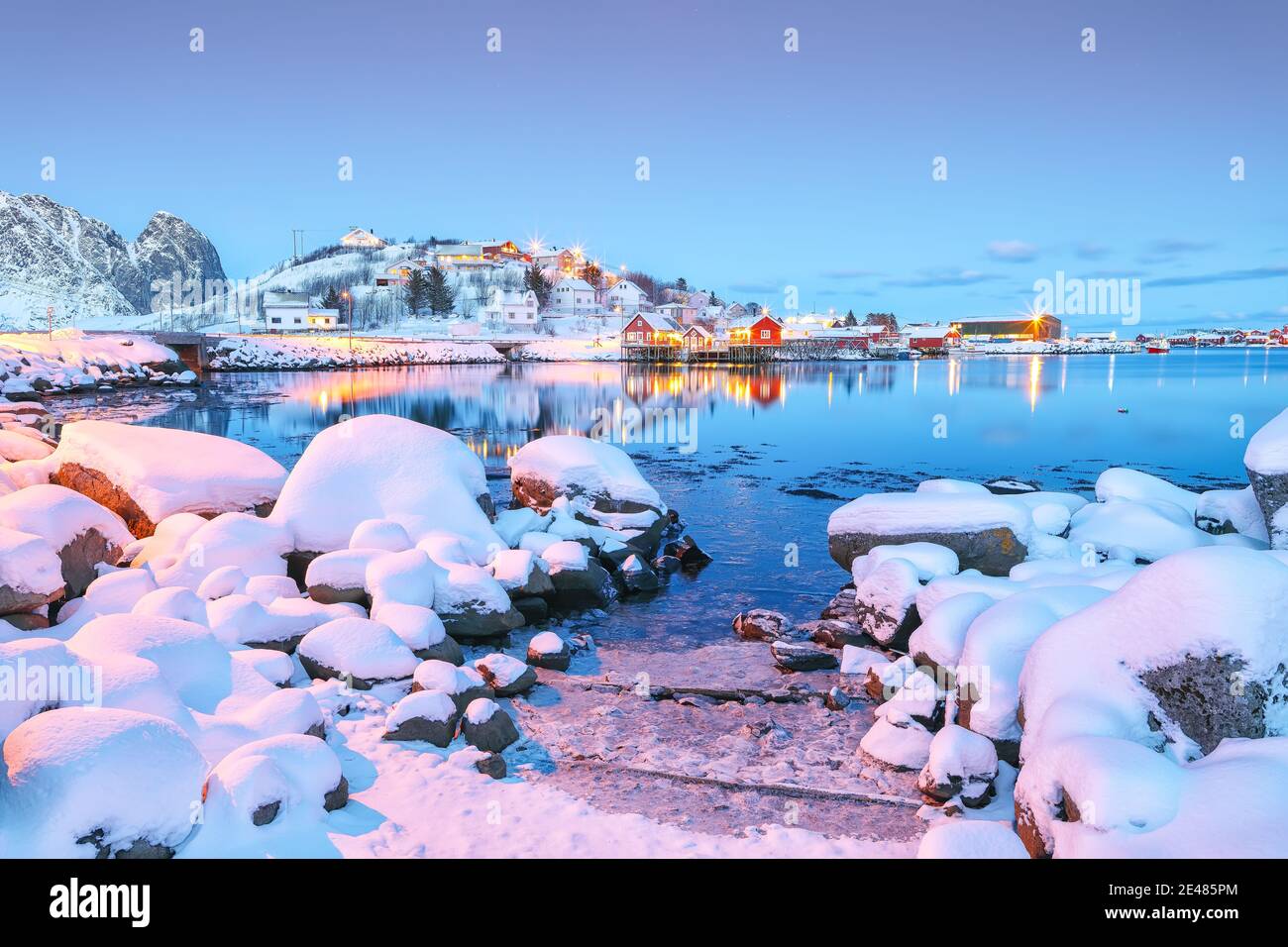 Dramatic evening cityscape of Reine town. Red rorbuers on the shoore of ...