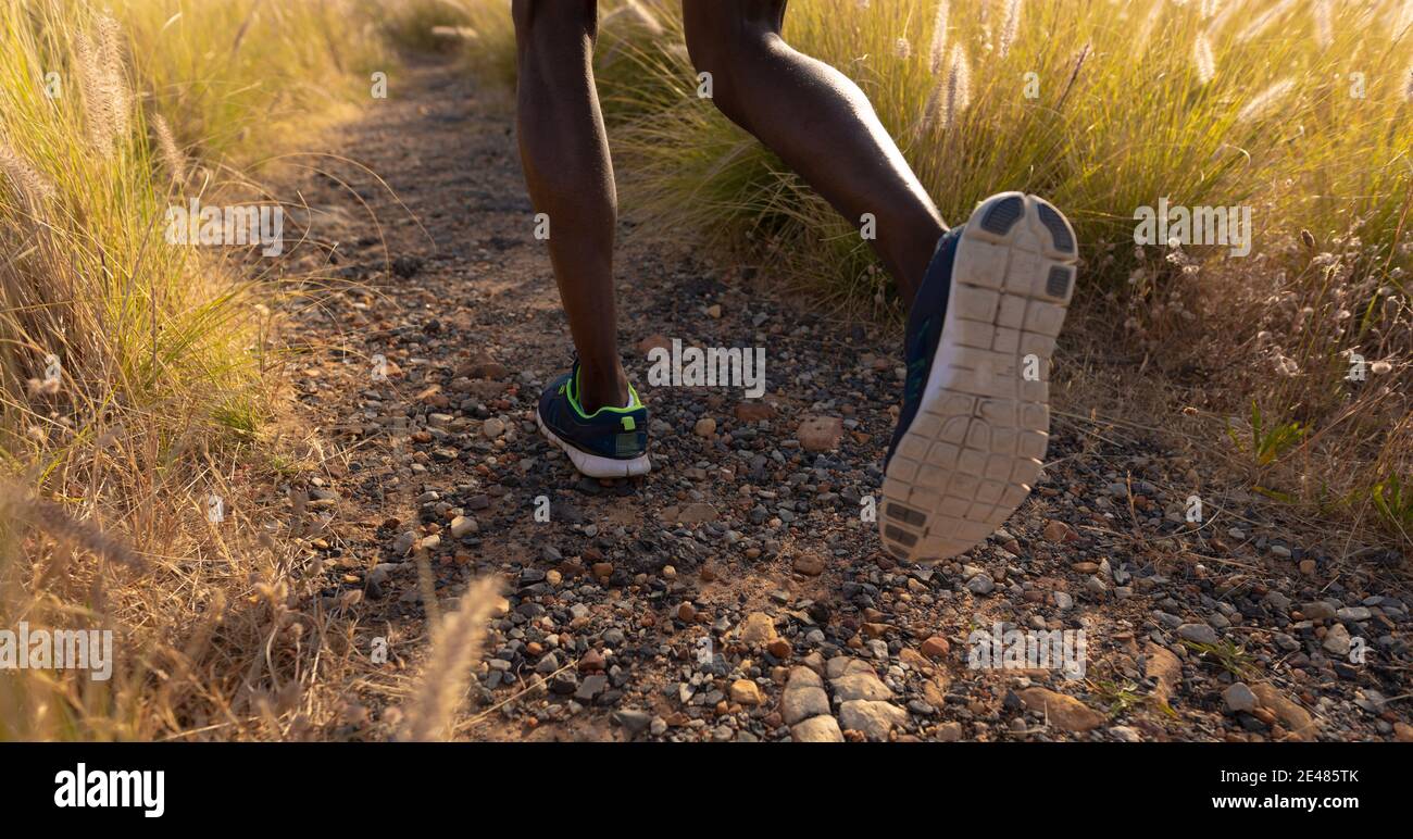 Fit african american man in sportswear running through tall grass Stock ...