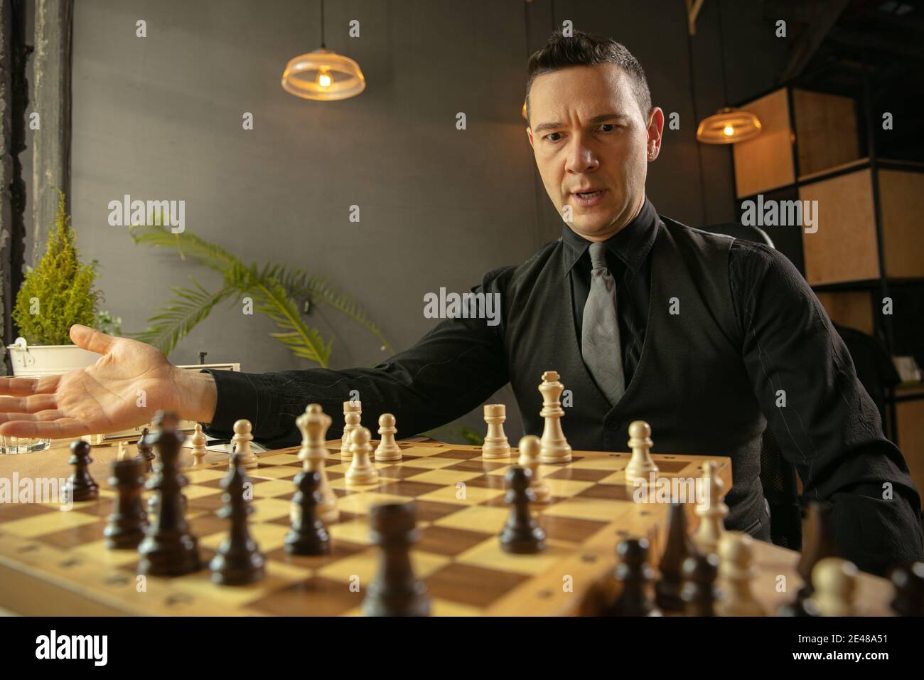Young Caucasian man chess player sitting at home and playing chess ...