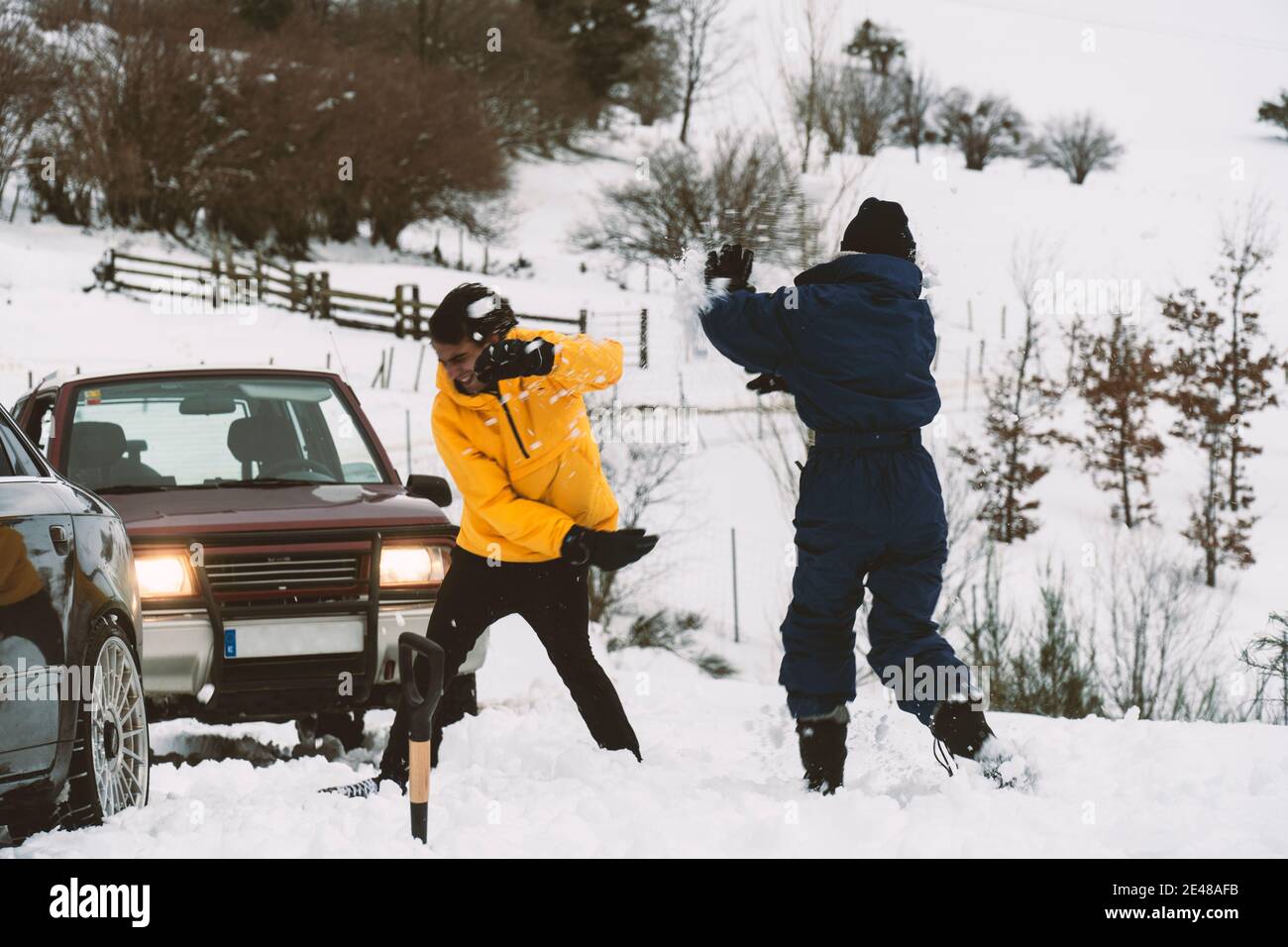 Two friends fighting with snowballs in the snow with the 4wd car on the ...