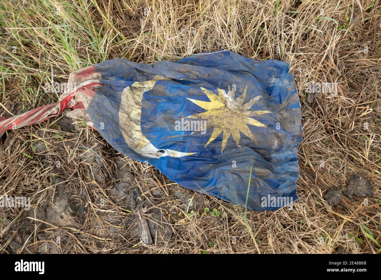 Torn and dirty flag of Malaysia thrown on the grassy ground Stock Photo ...