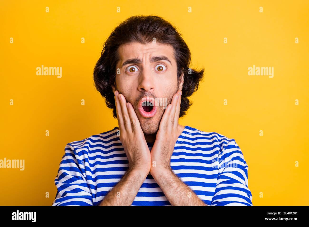 Portrait of astonished man look in camera touch hands face wear ...