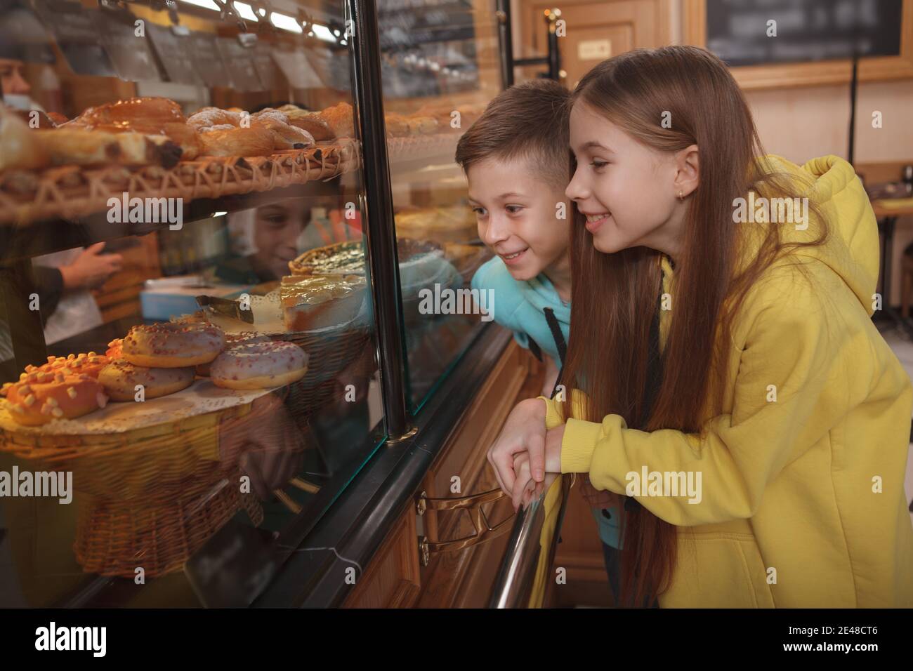 Two lovely twin kids choosing pastry from retail display, shopping at ...