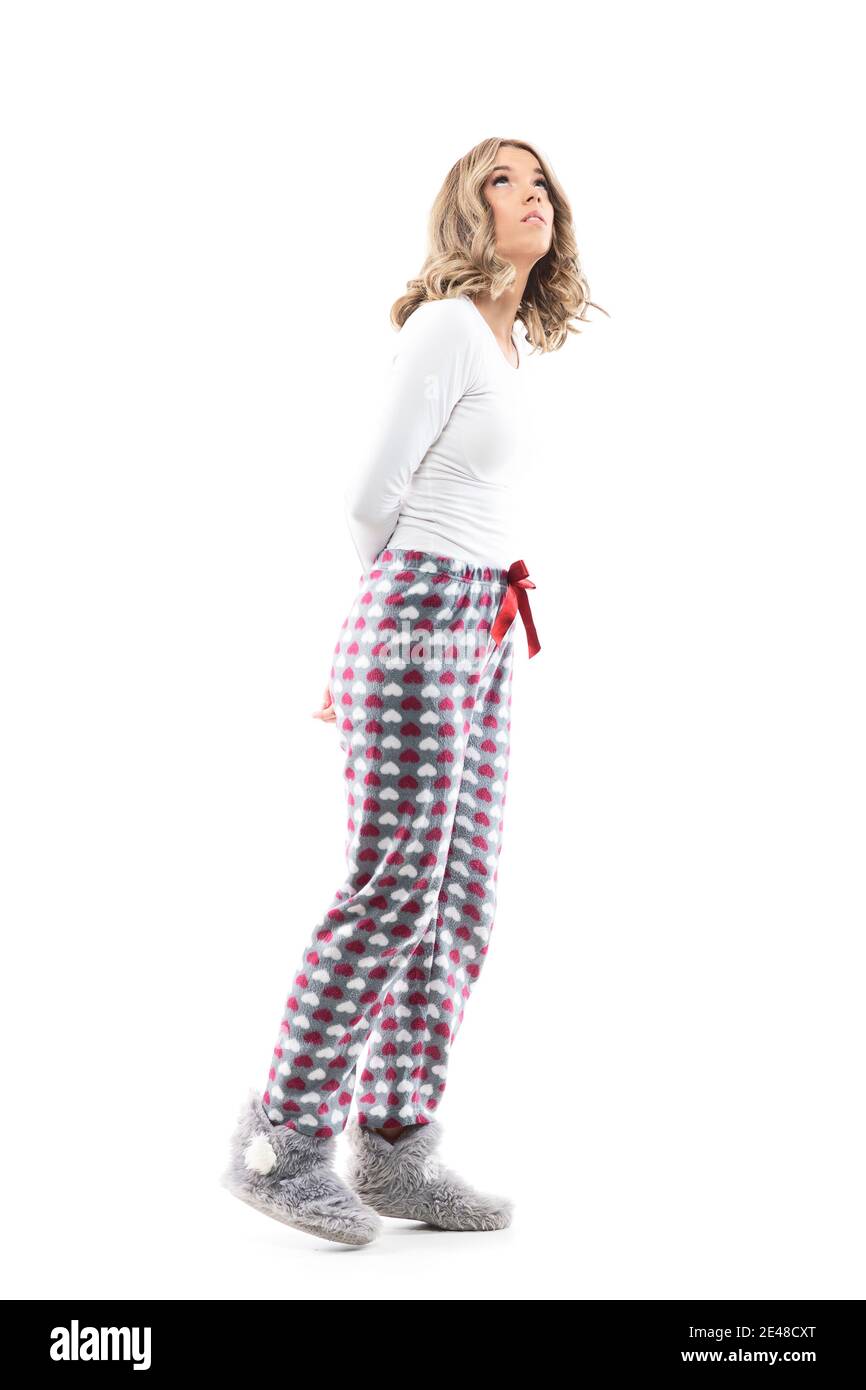 Side view of uncertain young woman walking and looking up in pajama ...