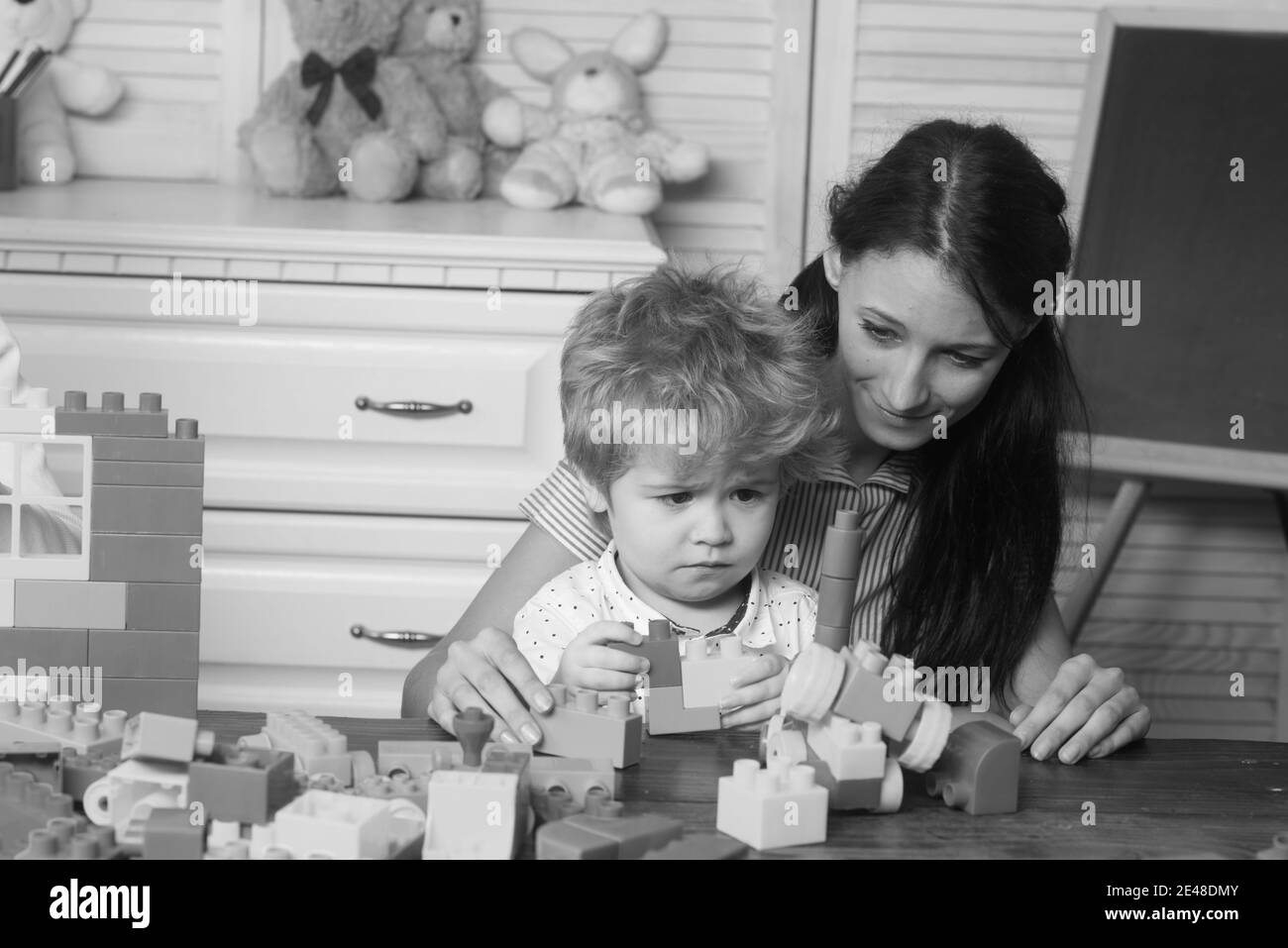 Parent and kid with busy faces make brick constructions. Mom and child ...
