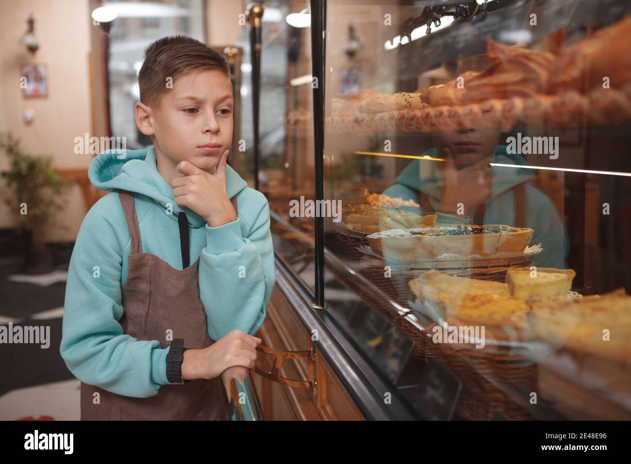 Cute young boy working at his parents bakery cafe, examining retail ...