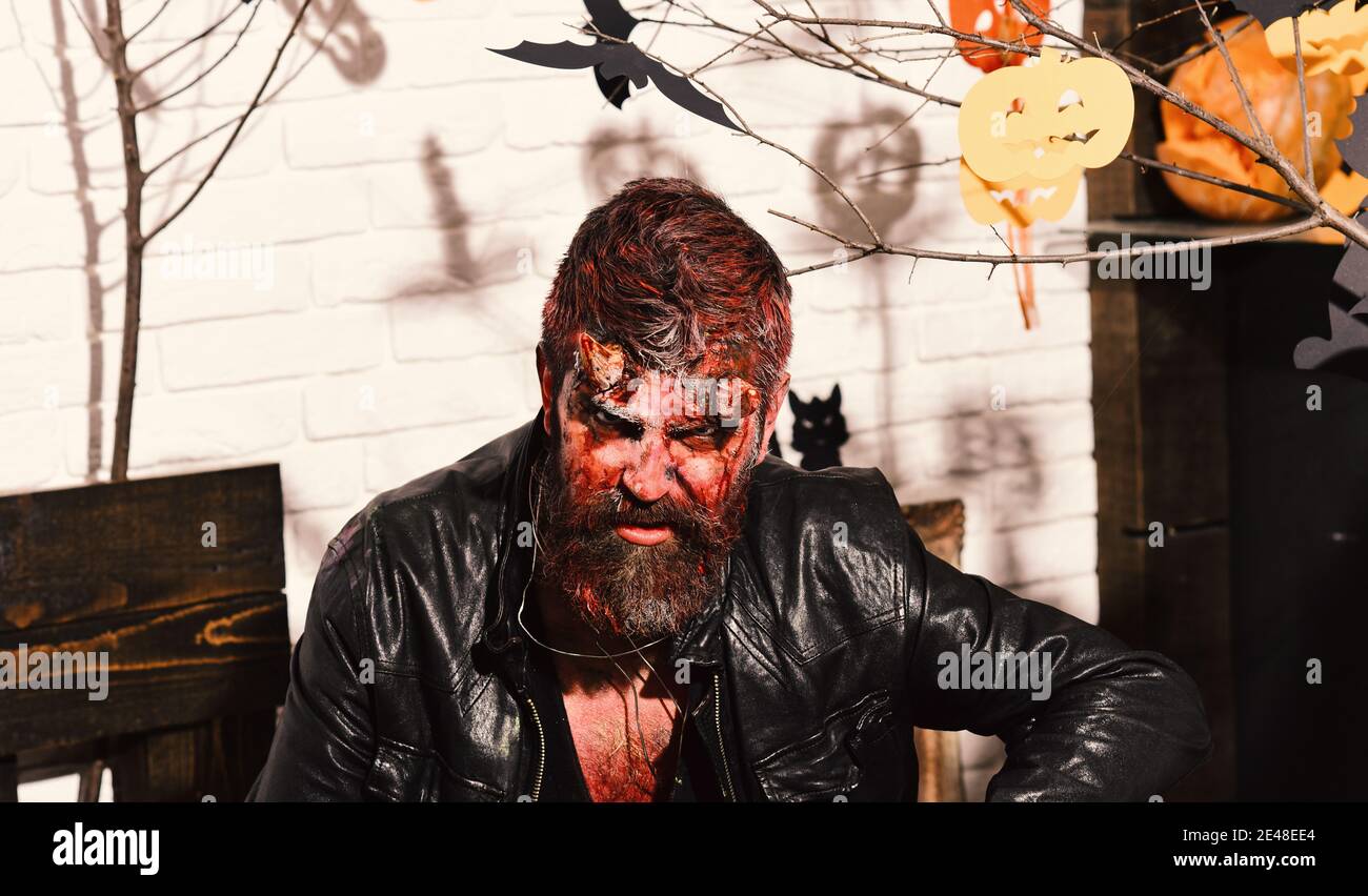 Man wearing scary makeup with Halloween pumpkins and bats decor on ...