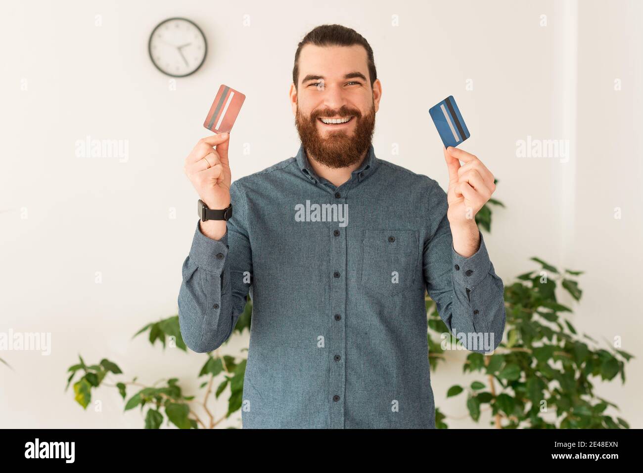 Portrait of happy office worker man showing two credit card, red and ...