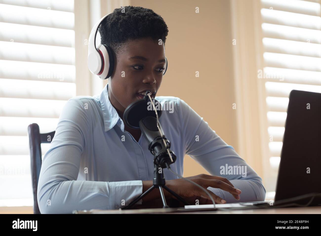 African american woman wearing headphones using microphone and laptop ...