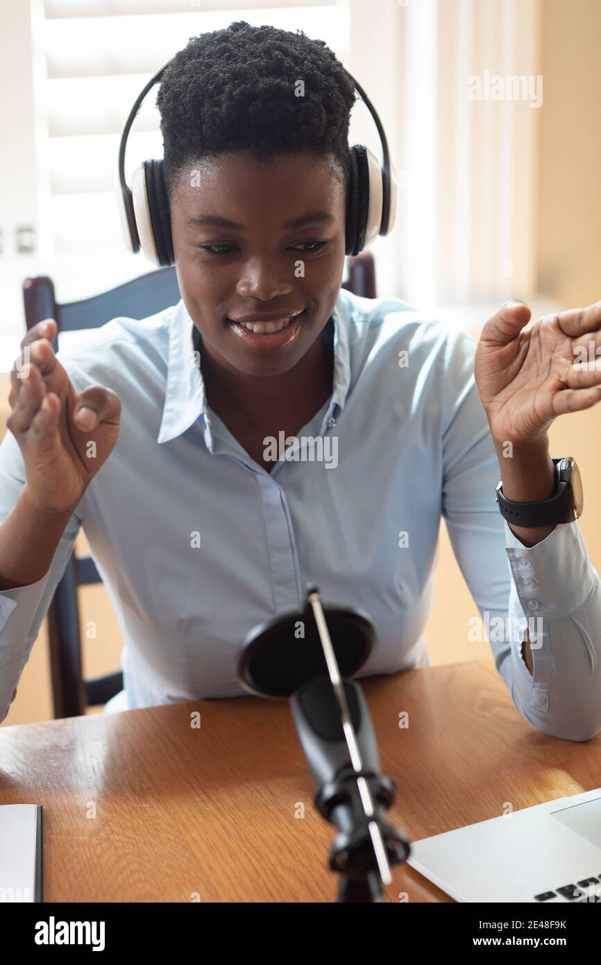 African american woman wearing headphones using microphone and laptop ...