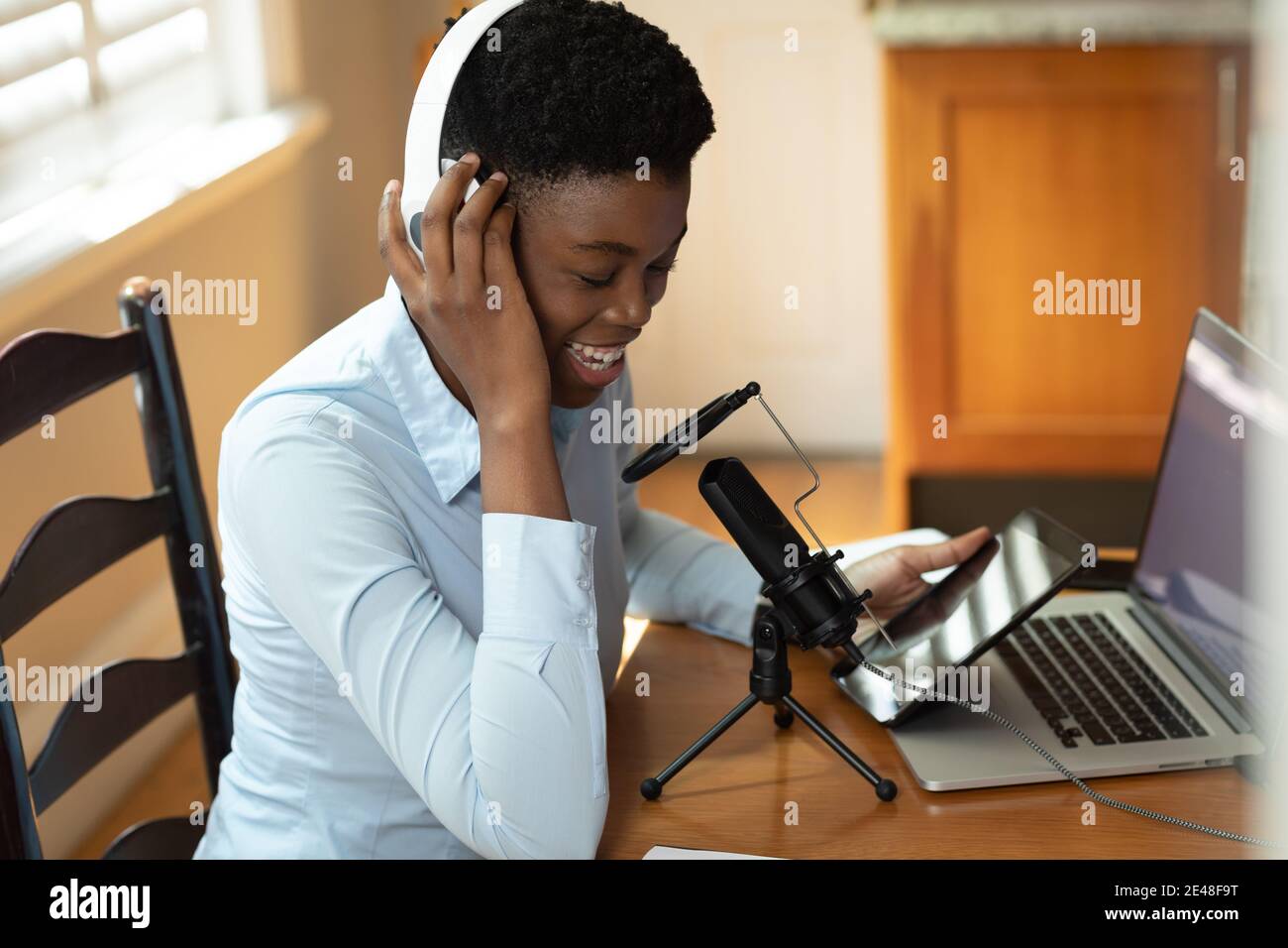African american woman wearing headphones using microphone and laptop ...
