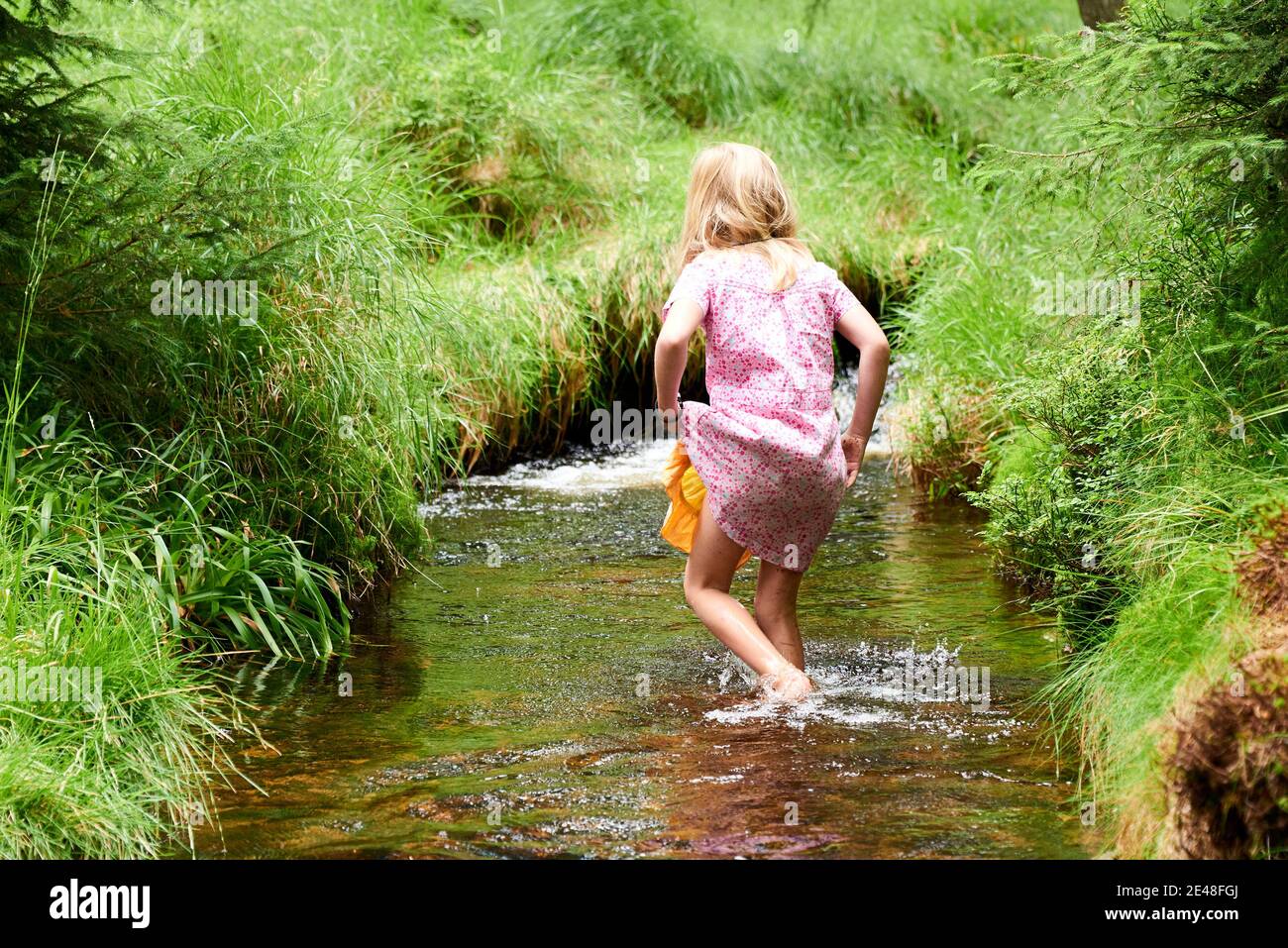 Child cute courageous blond girl playing in the creek. Brave girl ...