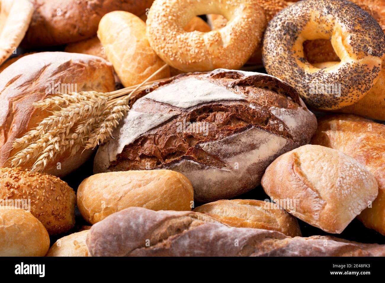 various types of fresh bread with wheat ears as background Stock Photo ...