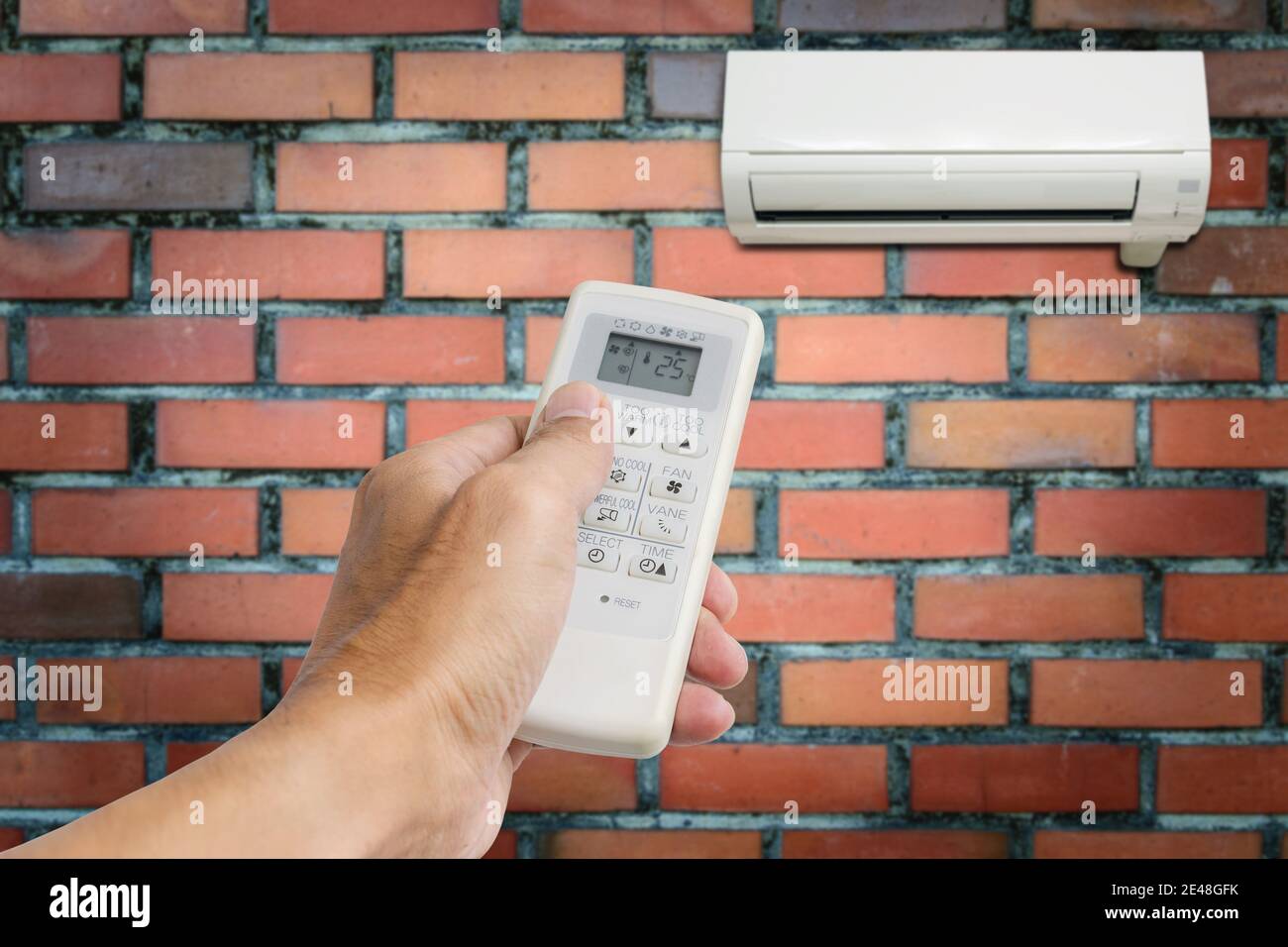 Hand holding the remote control to control the air conditioning on the ...