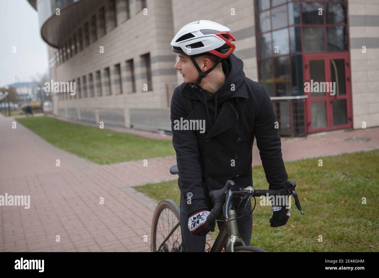 Male cyclist wearing helmet, looking over his shoulder while riding ...