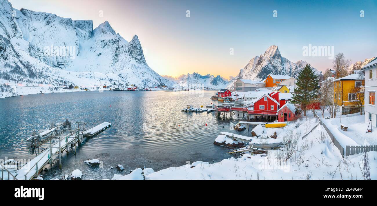 Dramatic evening cityscape of Reine town. Red rorbuers on the shore of ...