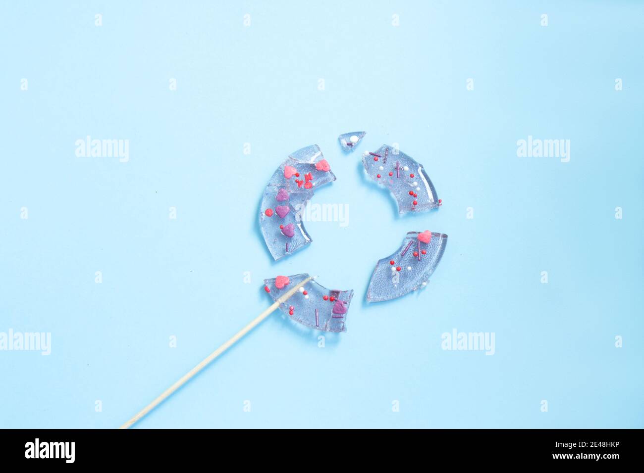 Broken in pieces transparent candy with little hearts on a stick ...