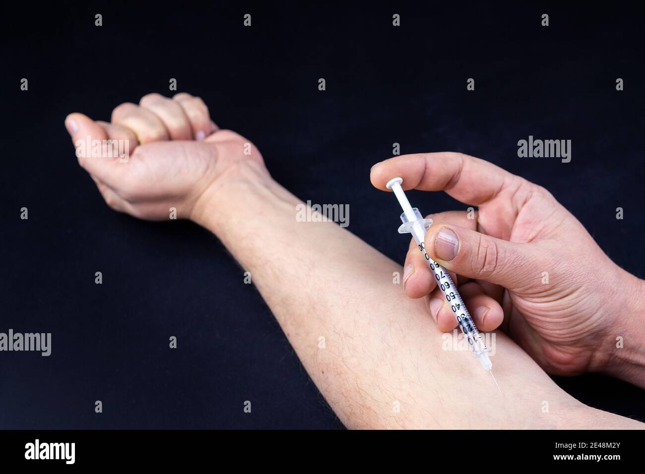 Hands of a drug addict with a syringe of narcotic cocaine or heroin to ...