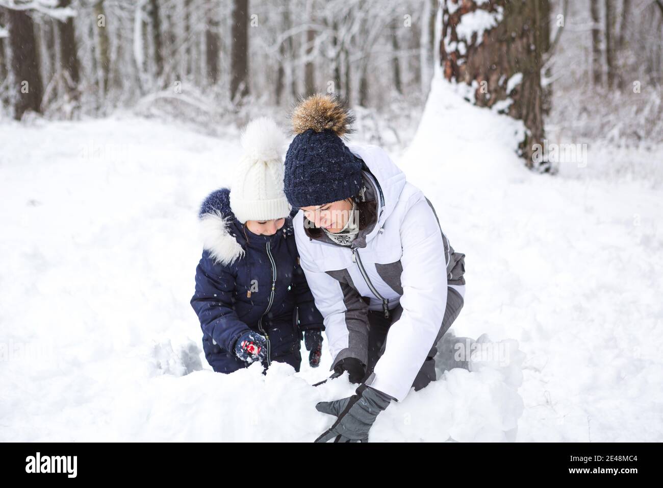 Mom and daughter play snow games, build a fortress, make snowballs ...
