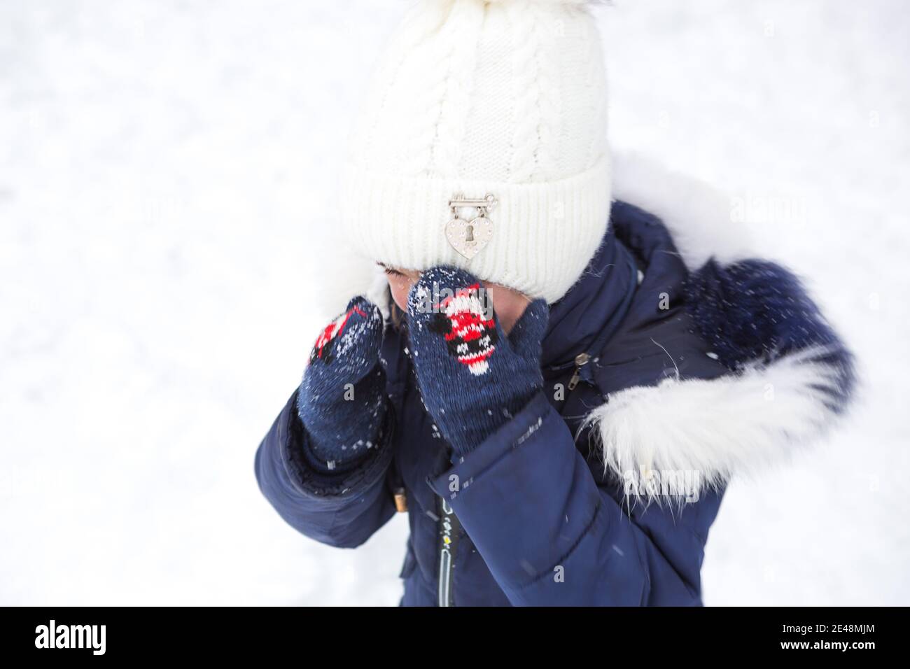 Little girl crying outside in winter. A child in warm clothes is upset ...