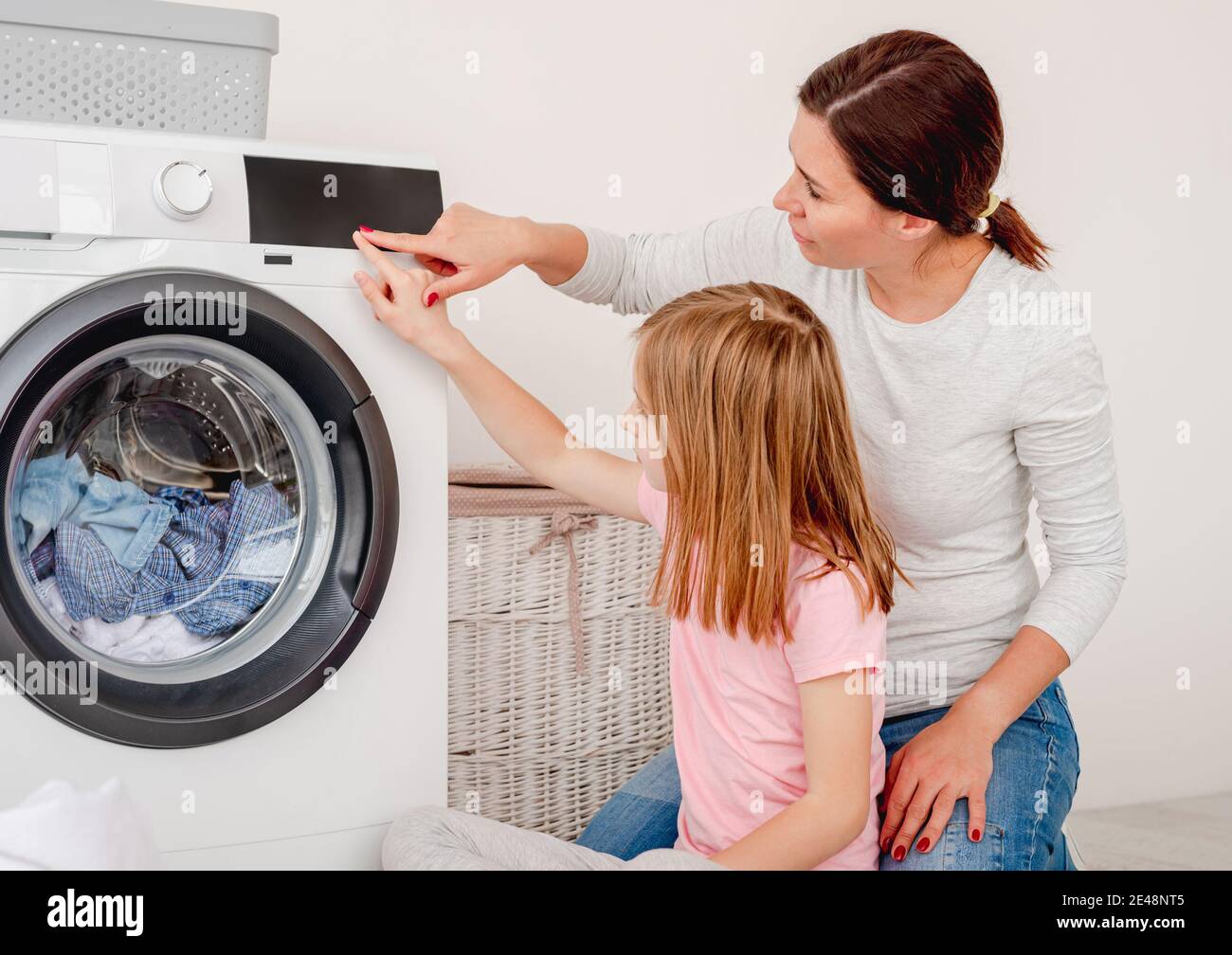 Mother teaching daughter operate washing machine Stock Photo - Alamy