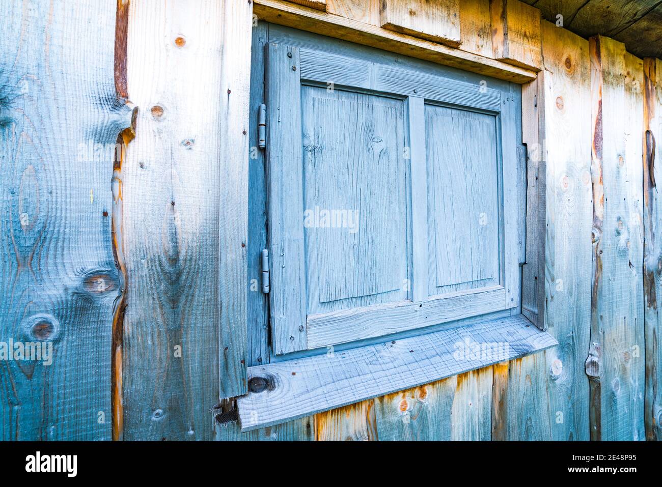 Very small closed window in a beautiful wooden wall of an old house ...