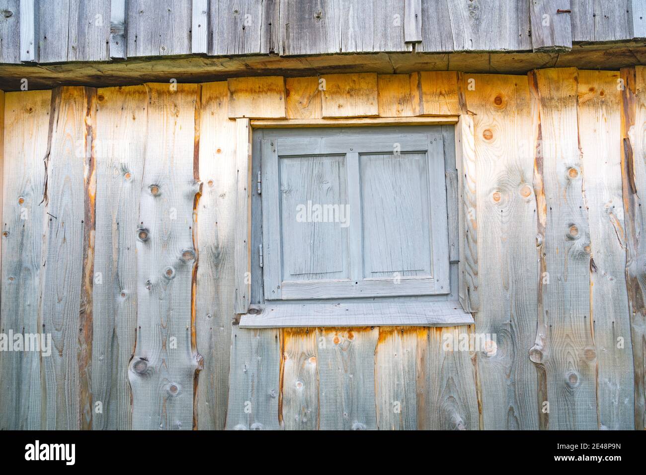 Very small closed window in a beautiful wooden wall of an old house ...