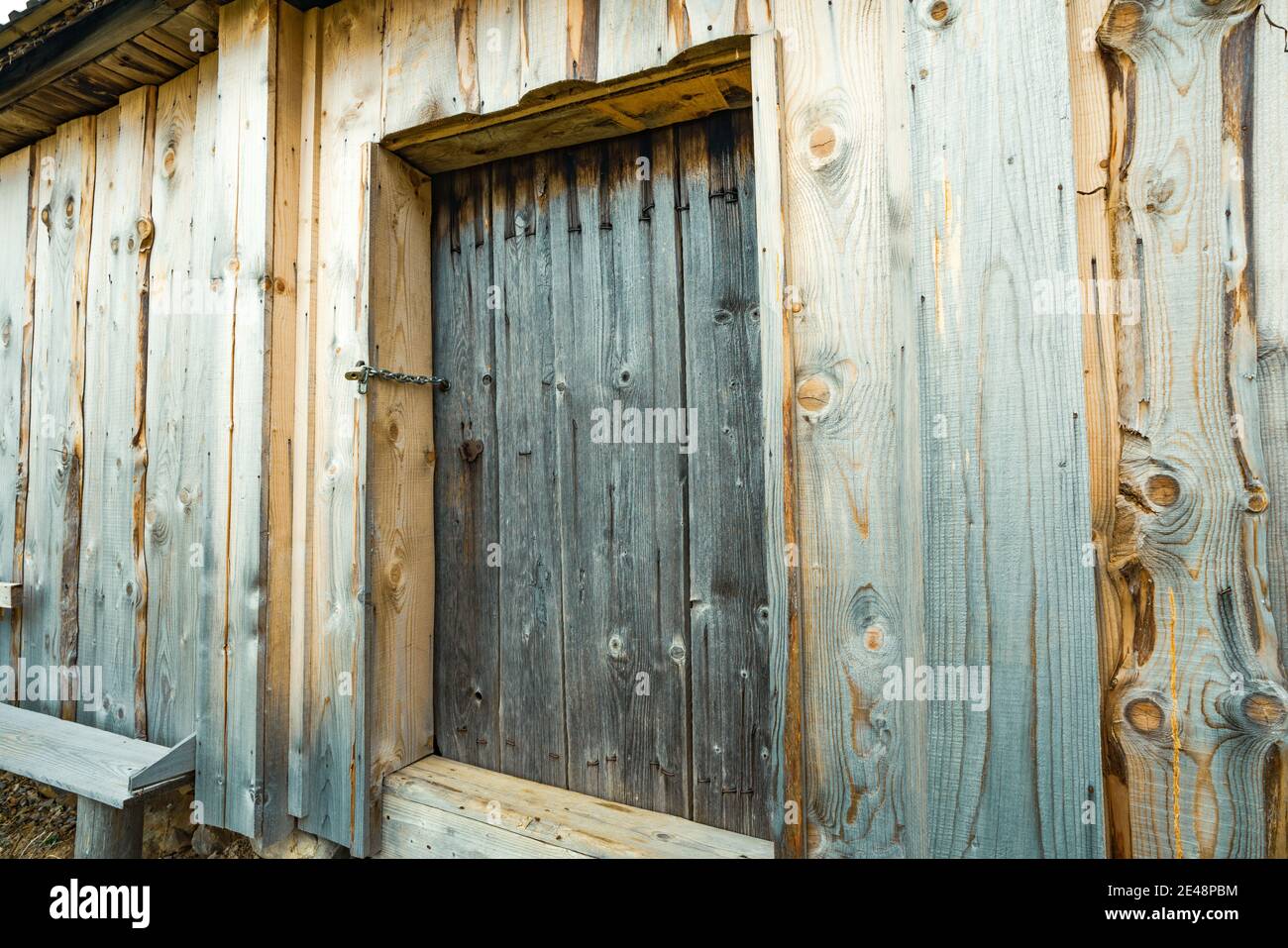 Small closed door in a beautiful wooden wall of an old house with ...