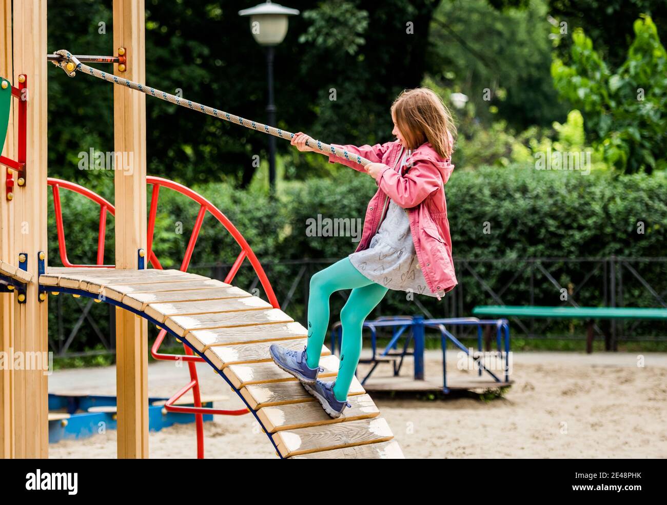 Little girl climbing rope on playground Stock Photo - Alamy