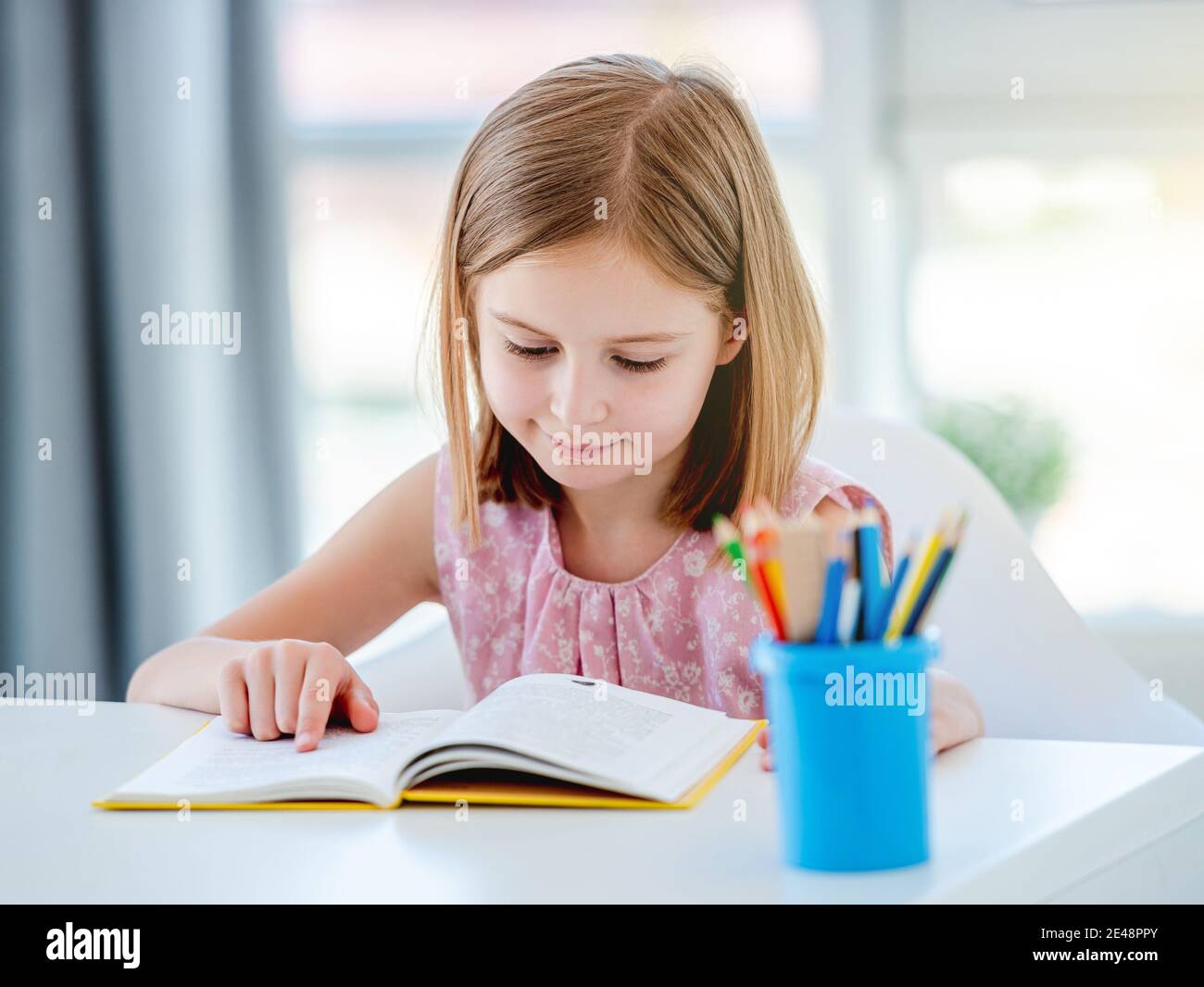 Little girl reading book in classroom Stock Photo - Alamy