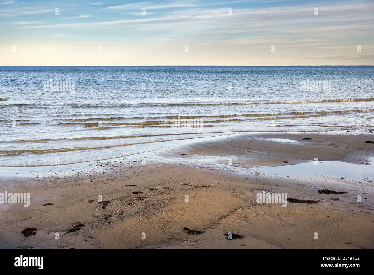 Wet sand beach, calm waves and view over the water to the horizon on ...