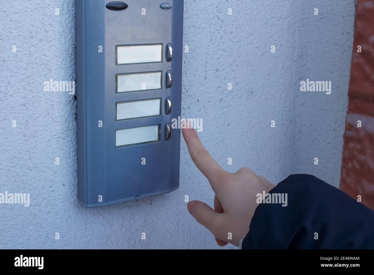 Woman is ringing the doorbell. The female hand presses a button on ...