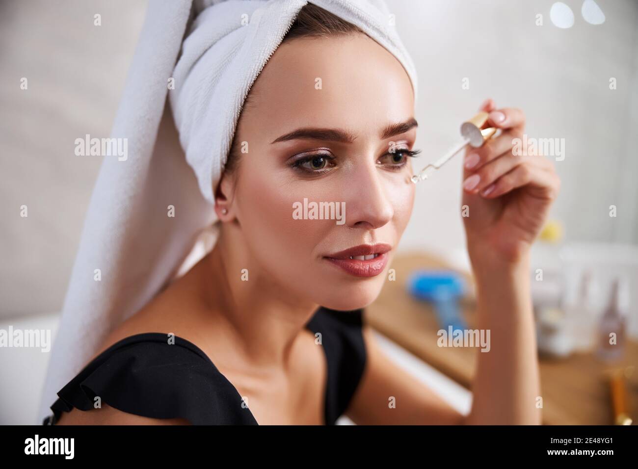 Beautiful young woman putting cosmetic product on her face Stock Photo ...