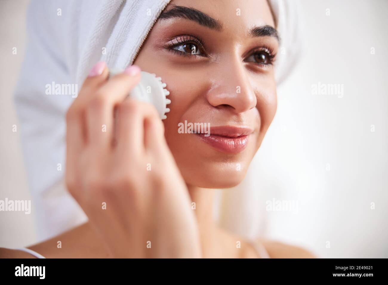 Radiant young woman using a rubber roller to massage her face Stock ...