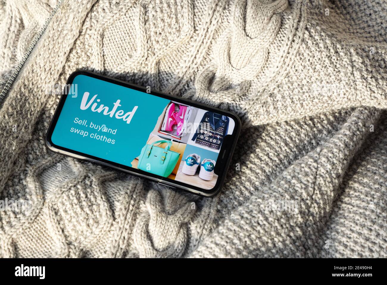 Iphone with Vinted logo on screen on vintage knitted fabric. Vinted is ...
