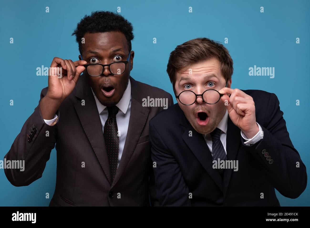 Two excited men looking at you wearing glasses being shocked. Studio ...
