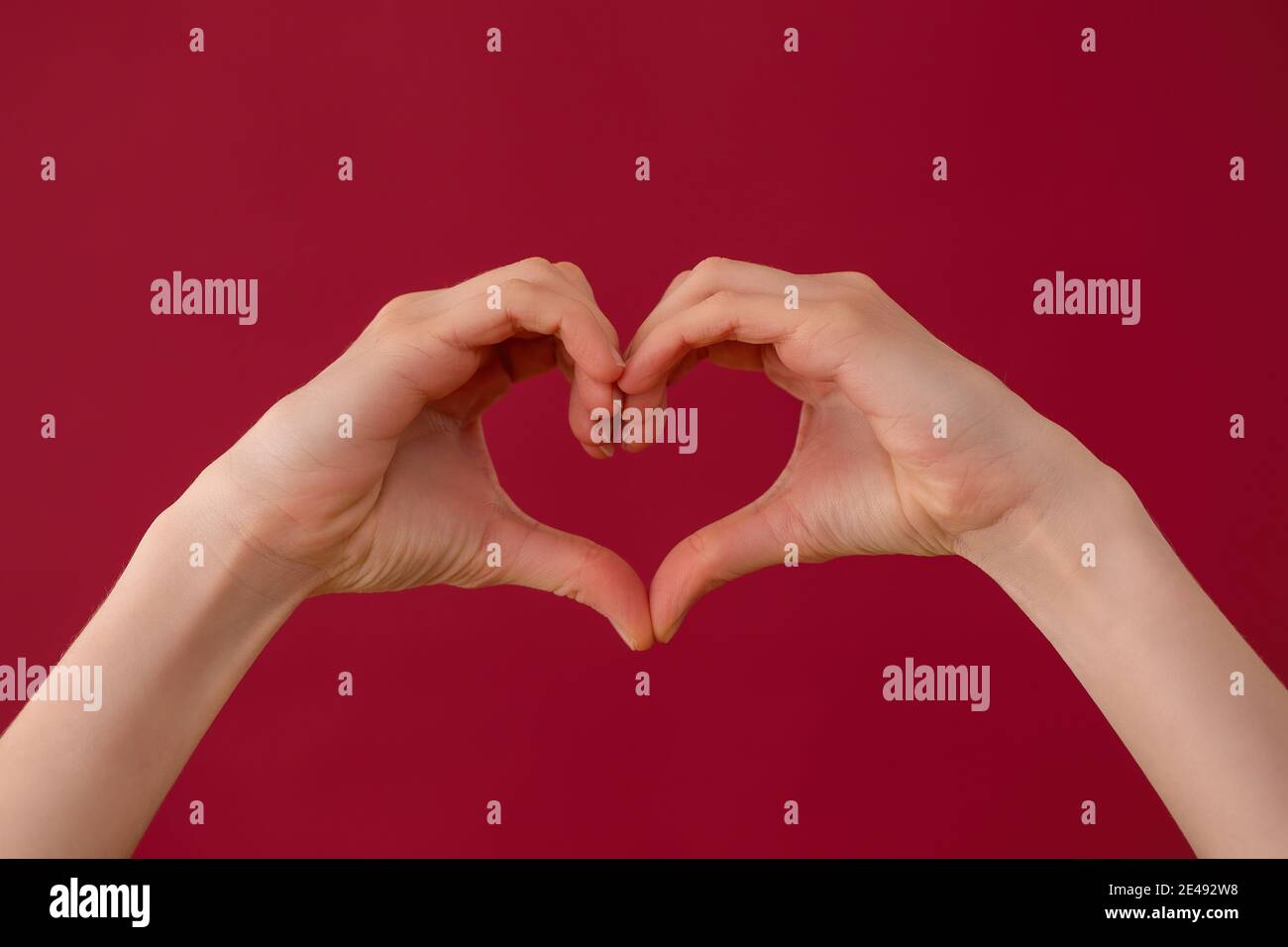 Female hands showing heart sign on red background in studio Stock Photo ...
