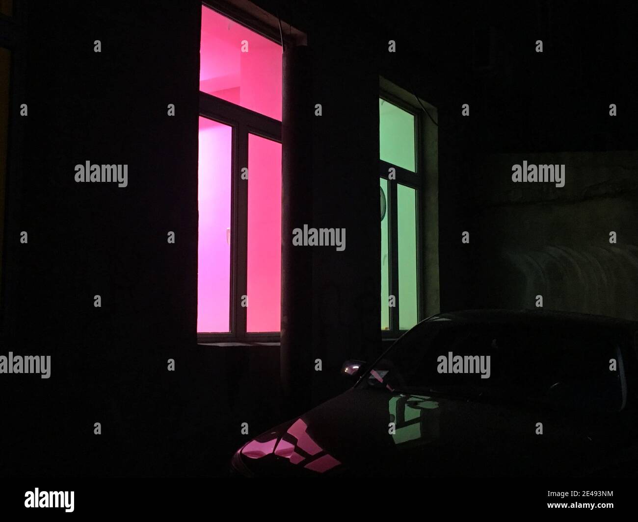Closeup of pink and green lights glowing in the dark from the windows ...
