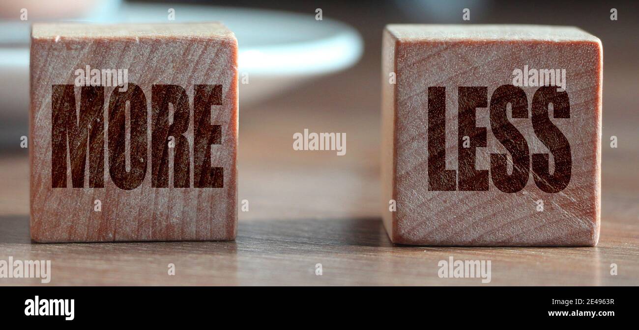 Wooden blocks on wooden table with More and Less signs. Decision making ...