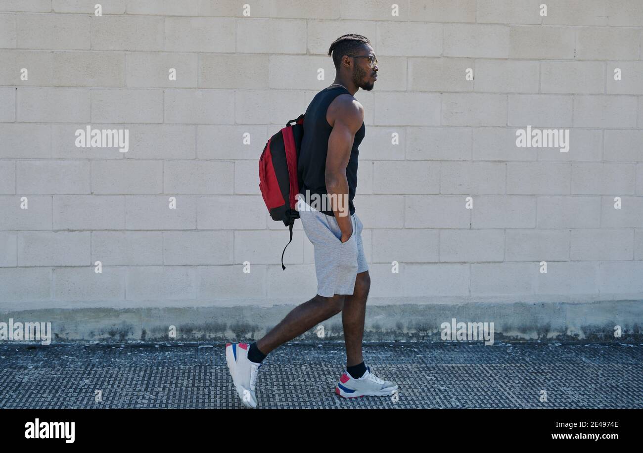 Young man walking past a wall Stock Photo - Alamy