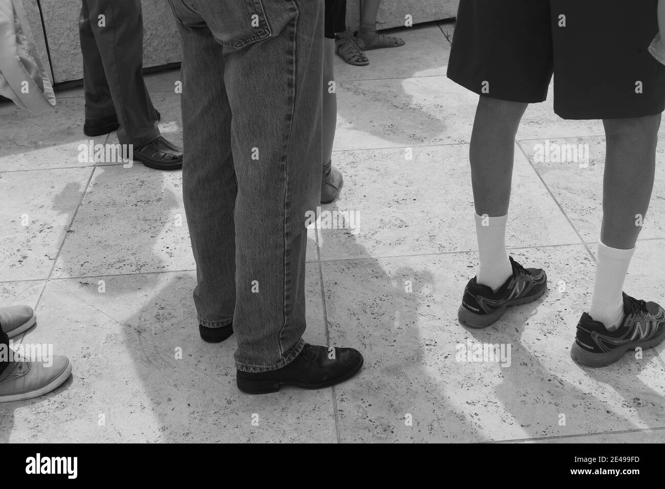 Closeup grayscale of people wearing different outfits standing in a ...